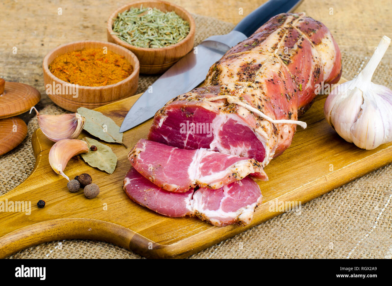 Traditional smoked pork neck with herbs and spices on wooden table ...