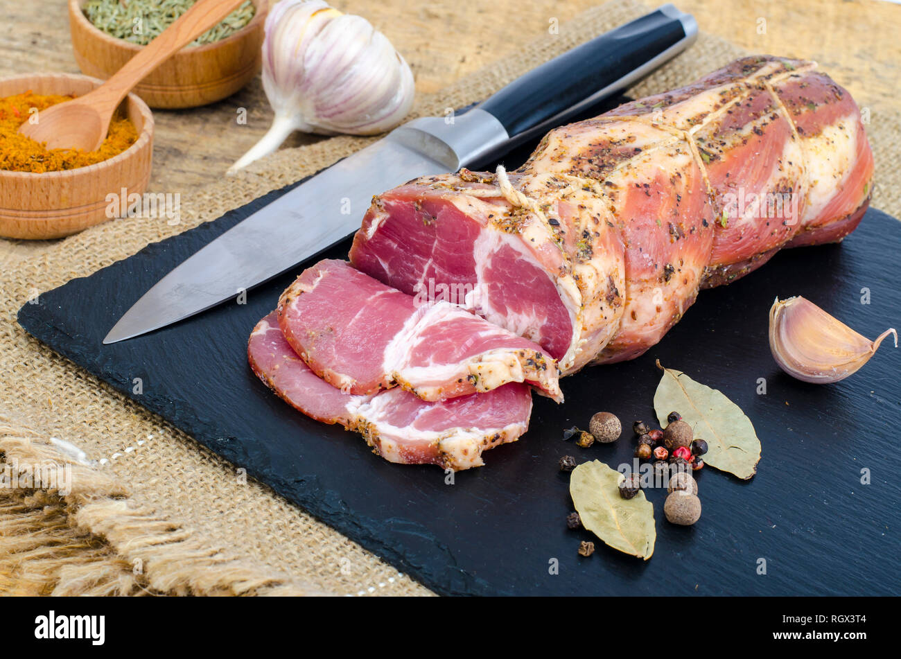 Traditional smoked pork neck with herbs and spices on wooden table ...