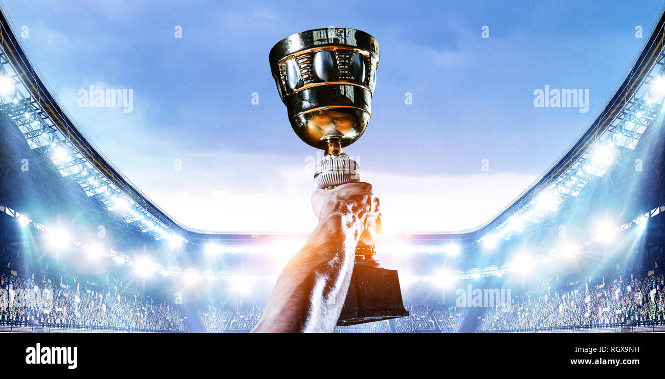 Hand of athlete holding cup trophy against stadium. Mixed media Stock ...