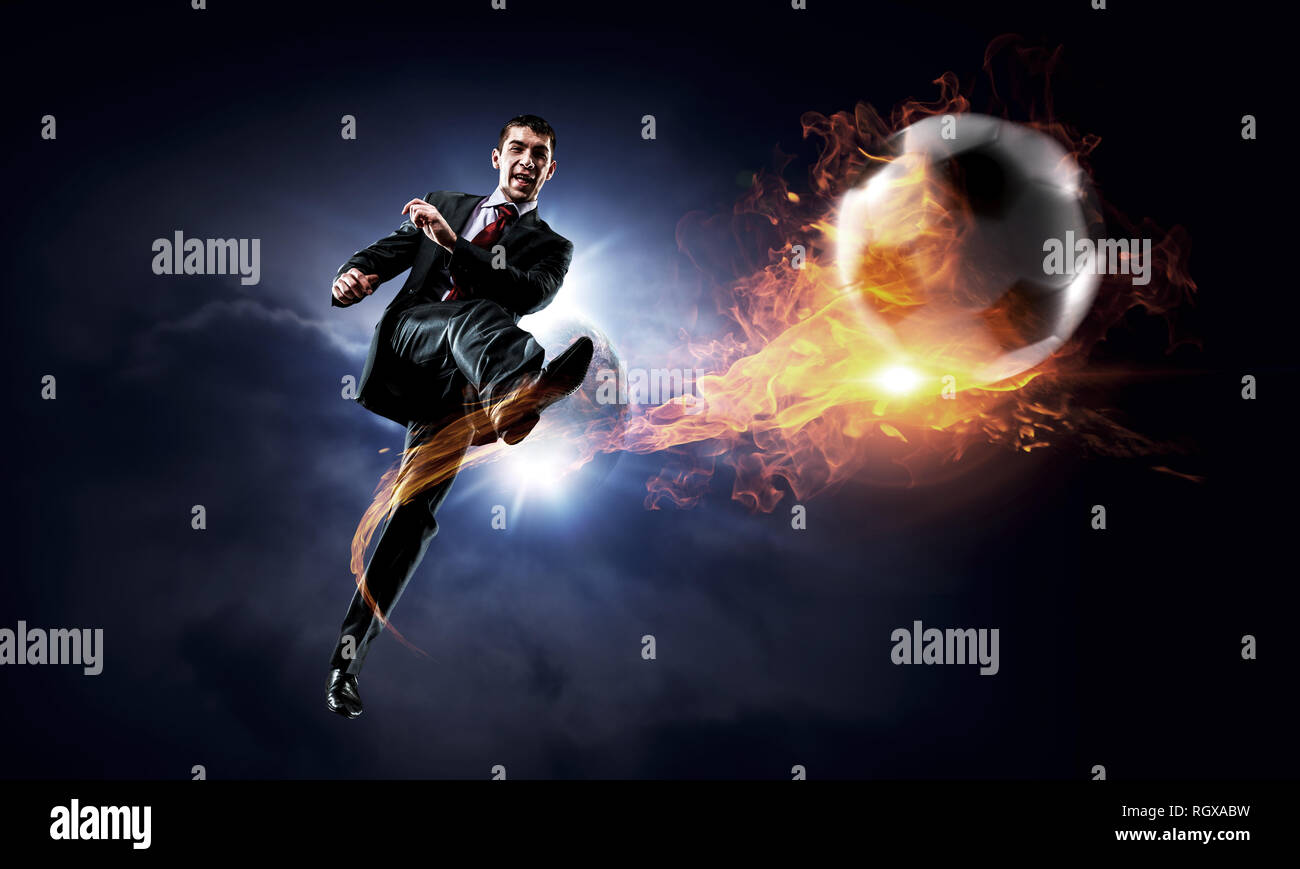 Furious businessman kicking ball in fire flames Stock Photo - Alamy