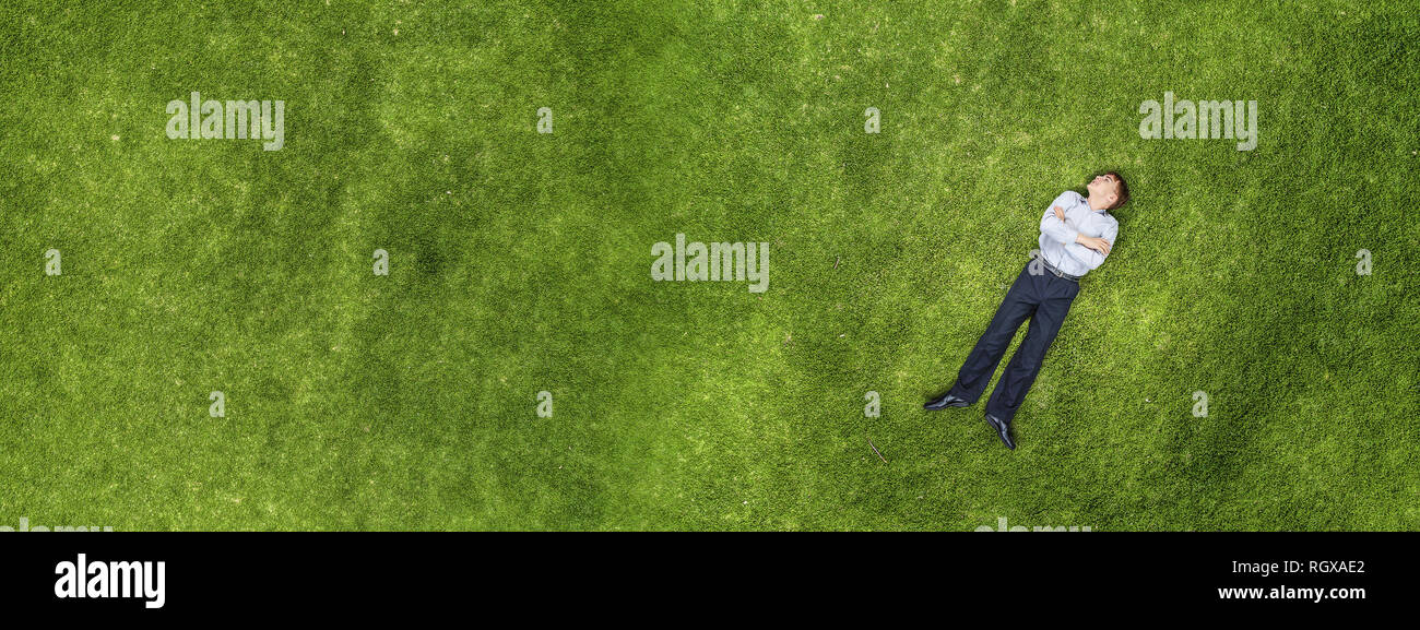Kid boy in suit lying on green grass Stock Photo - Alamy