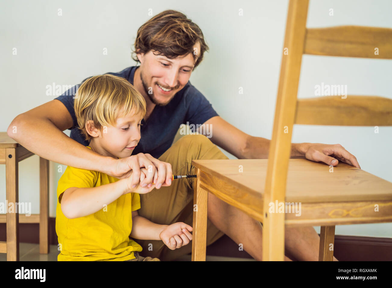 Father and son assembling furniture. Boy helping his dad at home. Happy ...