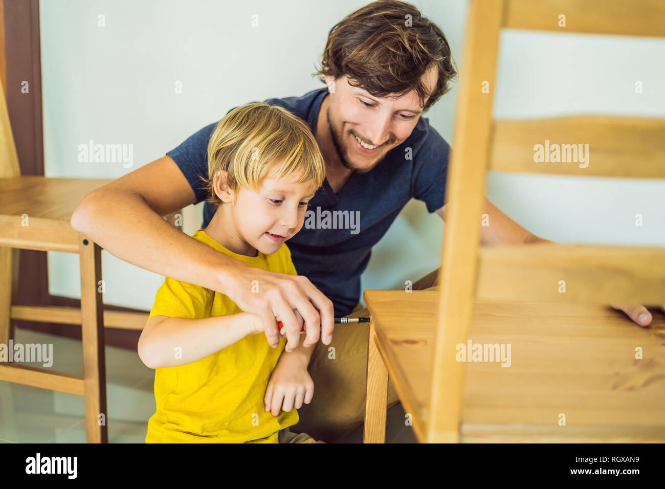 Father and son assembling furniture. Boy helping his dad at home. Happy ...