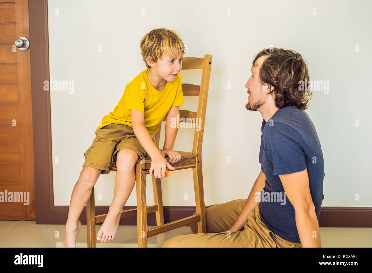Father and son assembling furniture. Boy helping his dad at home. Happy ...