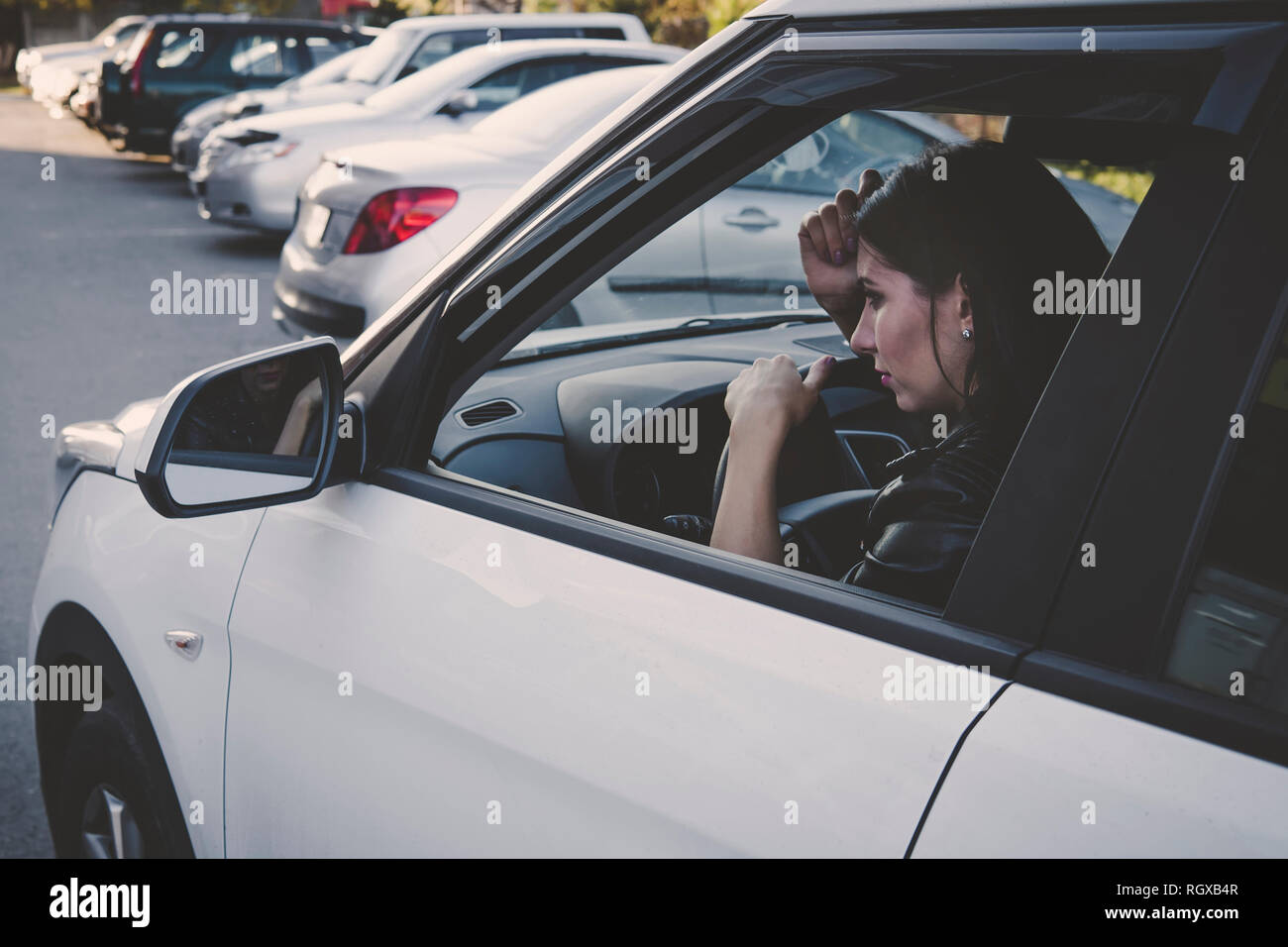 Side view of beautiful young woman looking in car side-view mirror ...