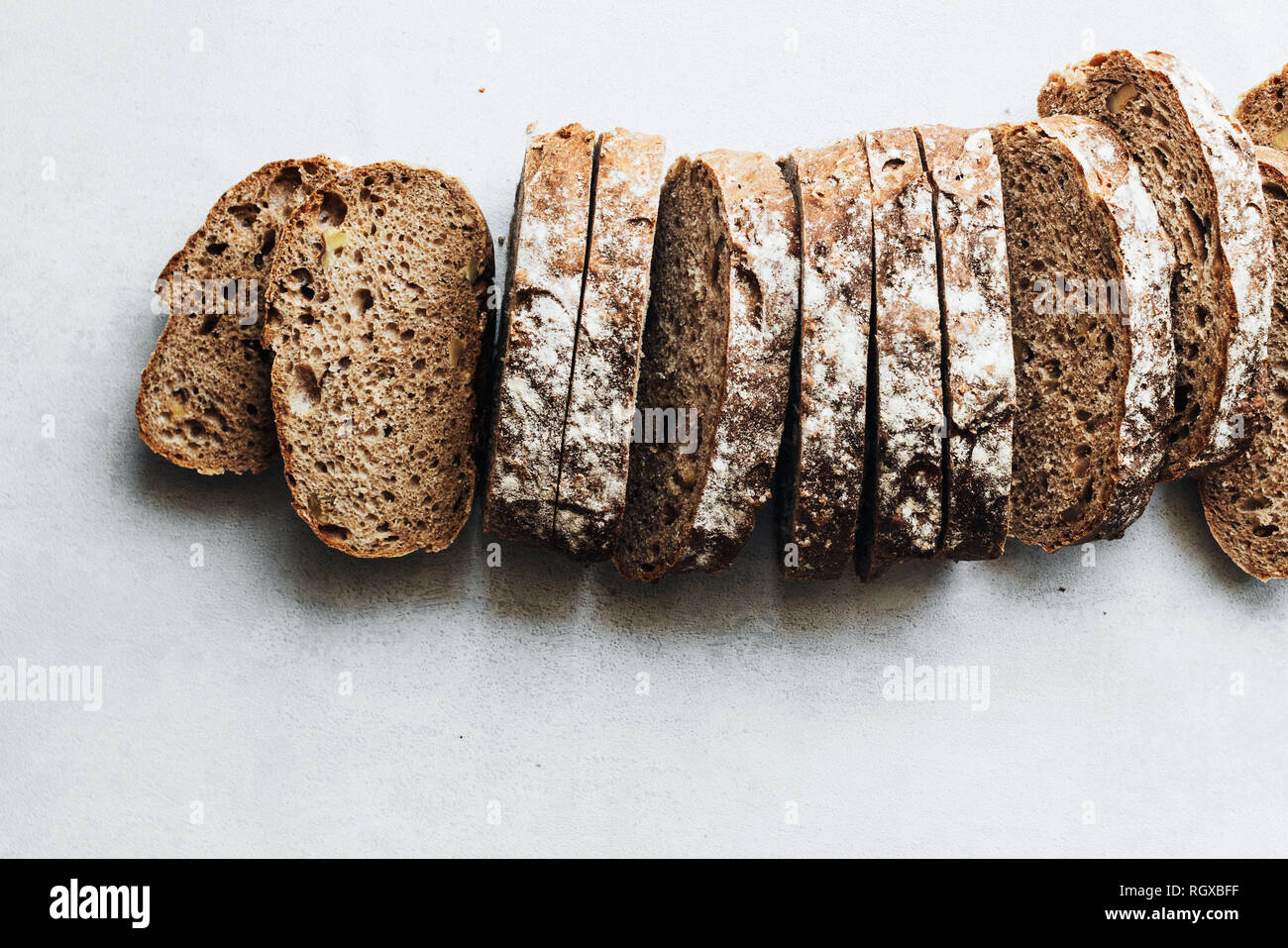 A loaf of bread laying on a white table, sliced, in black and white ...