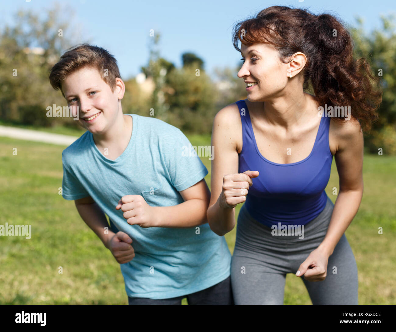 Portrait of young athletic woman and tween boy running outdoors at ...