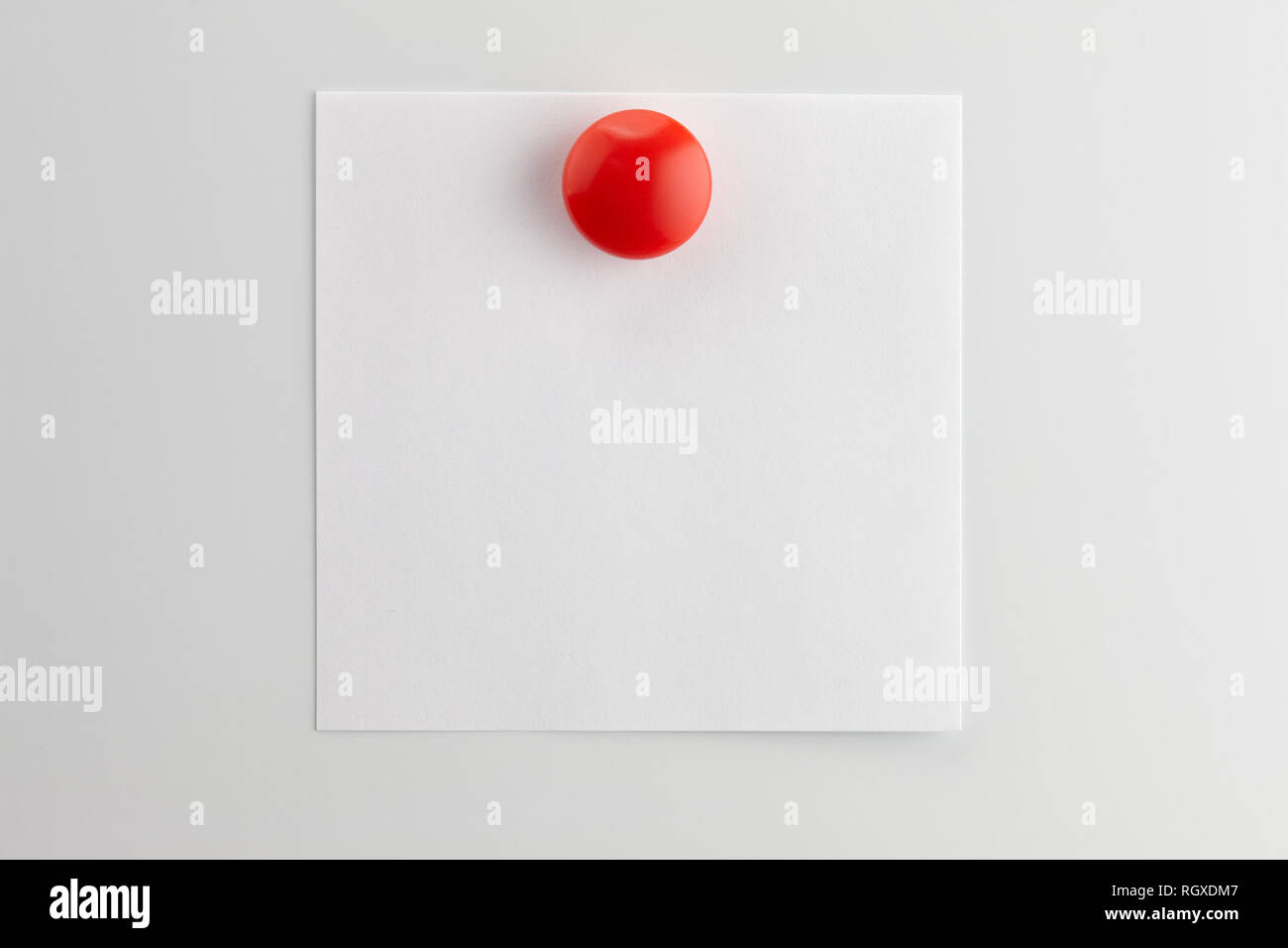 Square blank sheet of white paper pinned with a red button magnet on ... Square blank sheet of white paper pinned with a red button magnet on ...