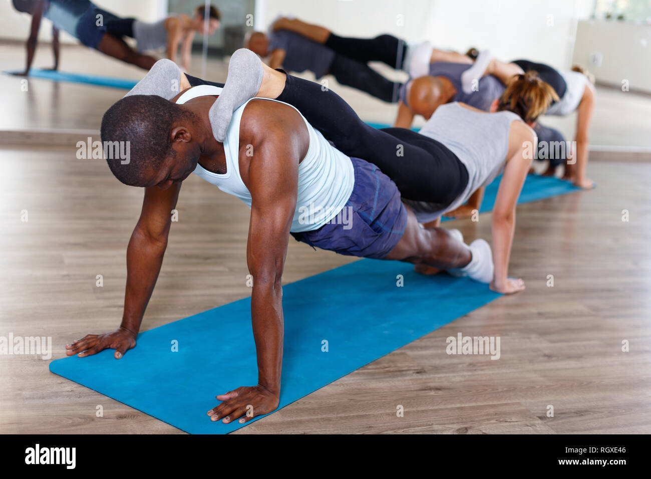Diligent efficient women and men exercising in pairs during yoga class ...