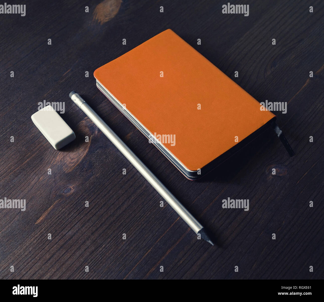 Orange notepad, pencil and eraser on wooden table Stock Photo - Alamy