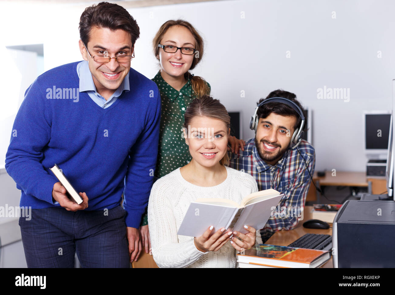Group of cheerful students reading textbook together while studying in ...