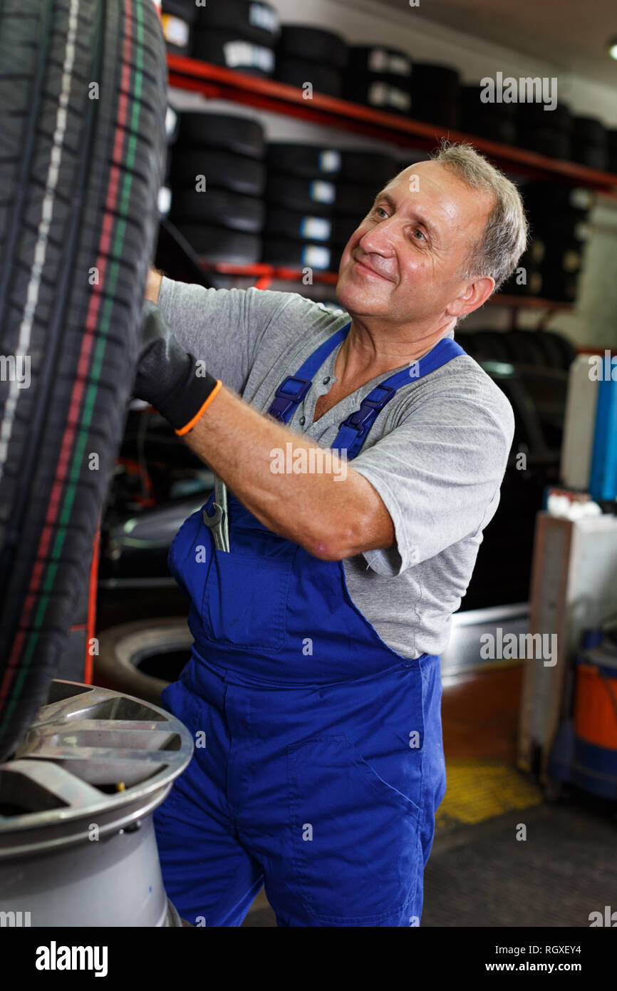 Professional male mechanician restoring tire and disc of car wheel in ...