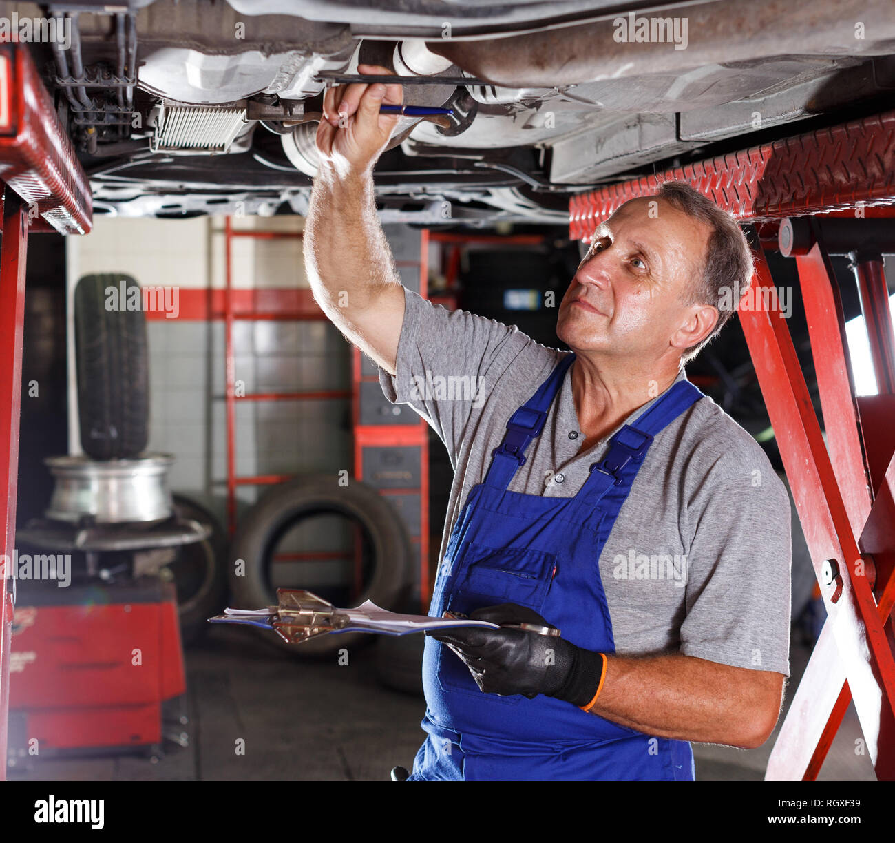Professional auto mechanic recording list of works on car repair in ...