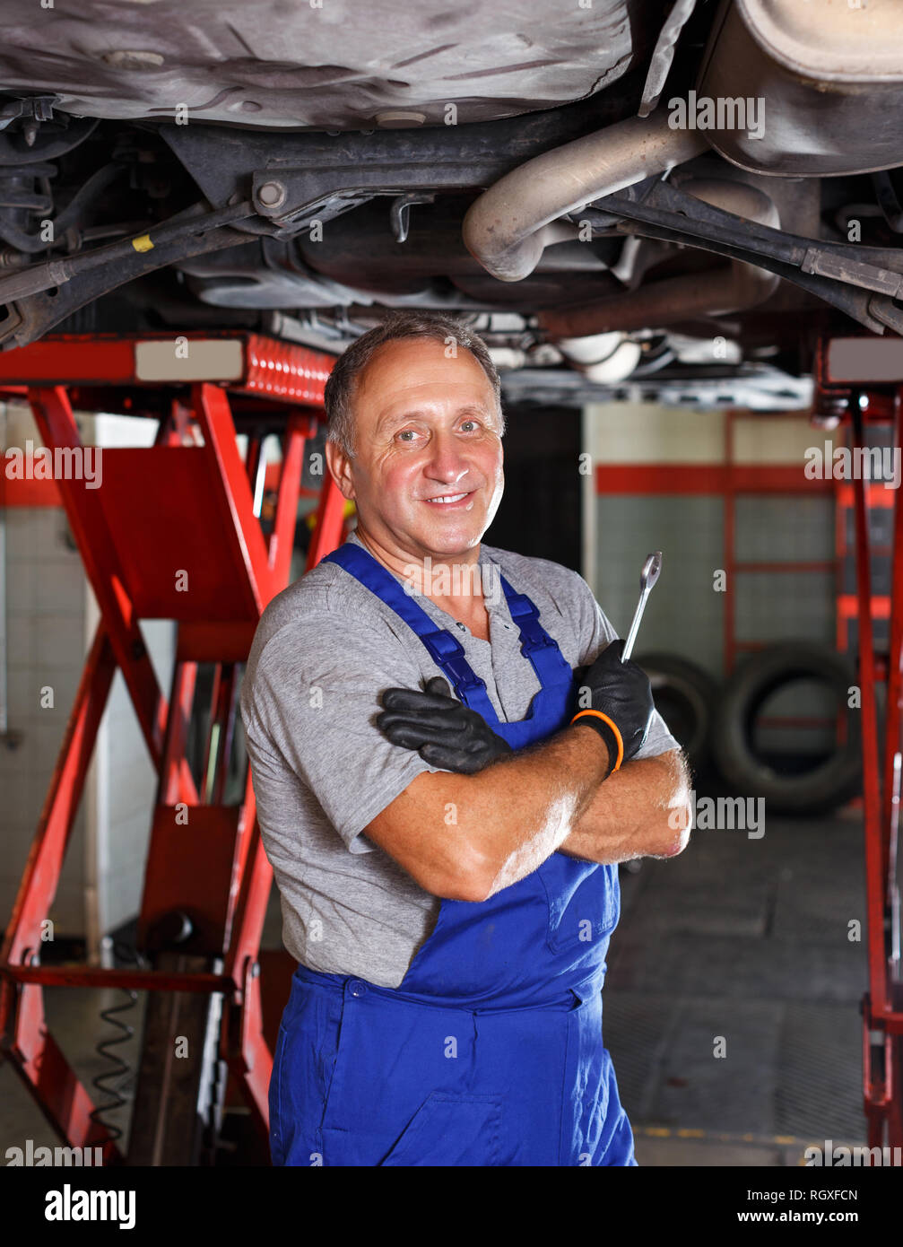 Portrait of smiling sinior man mechanic in overalls in auto repair shop ...