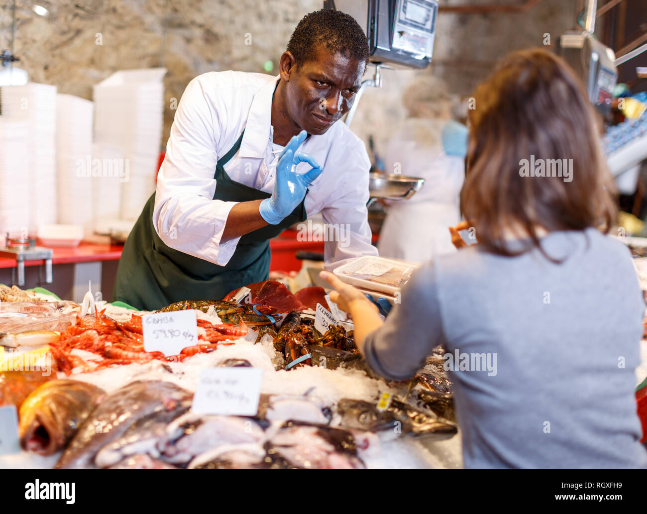 African American seller helping girl choose fish at seafood store Stock ...