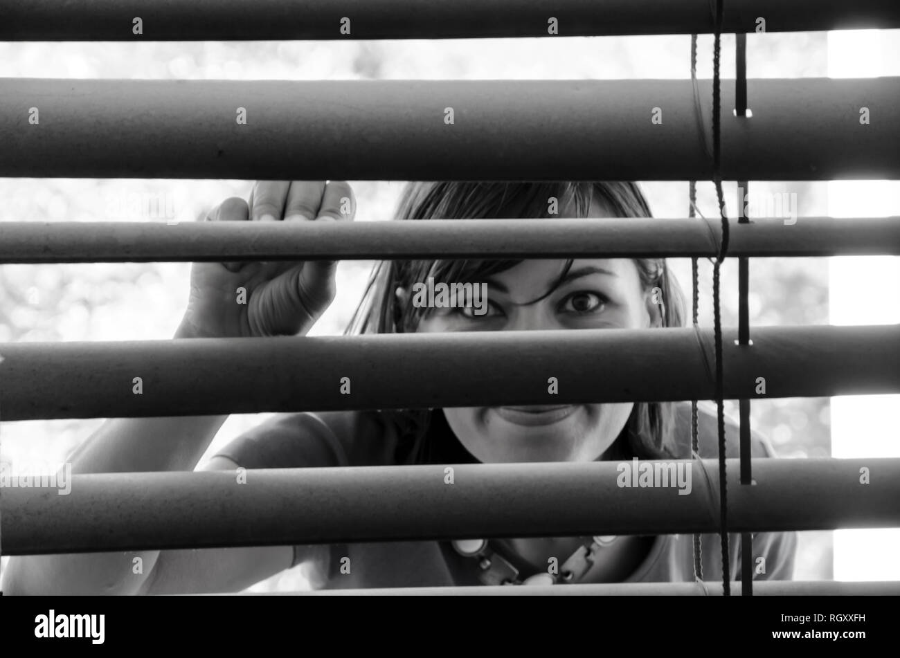 Woman looking through blinds in hi-res stock photography and images - Alamy