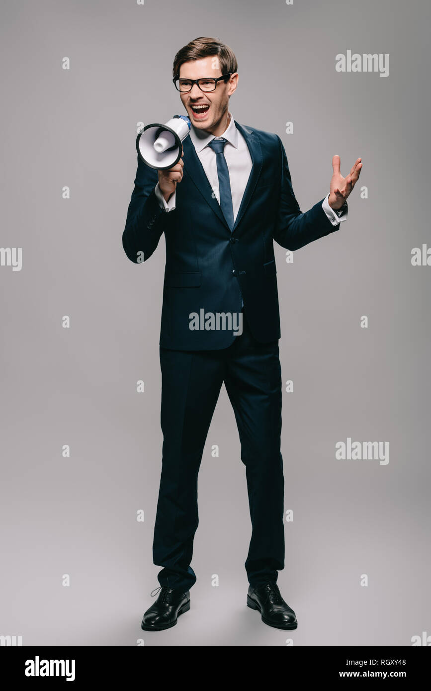 angry businessman in suit screaming in megaphone isolated on grey Stock ...