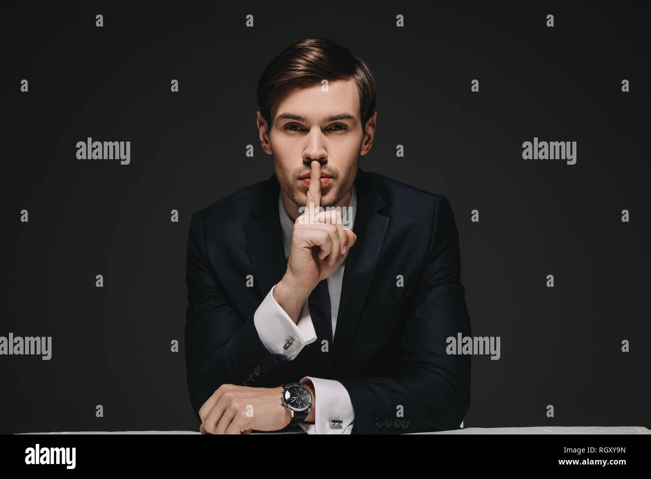 handsome man in suit showing hush sign isolated on black Stock Photo ...
