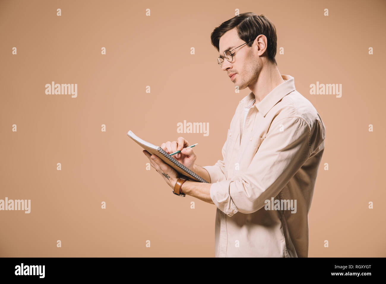thoughtful man in glasses writing notebook isolated on beige Stock ... thoughtful man in glasses writing notebook isolated on beige Stock ...