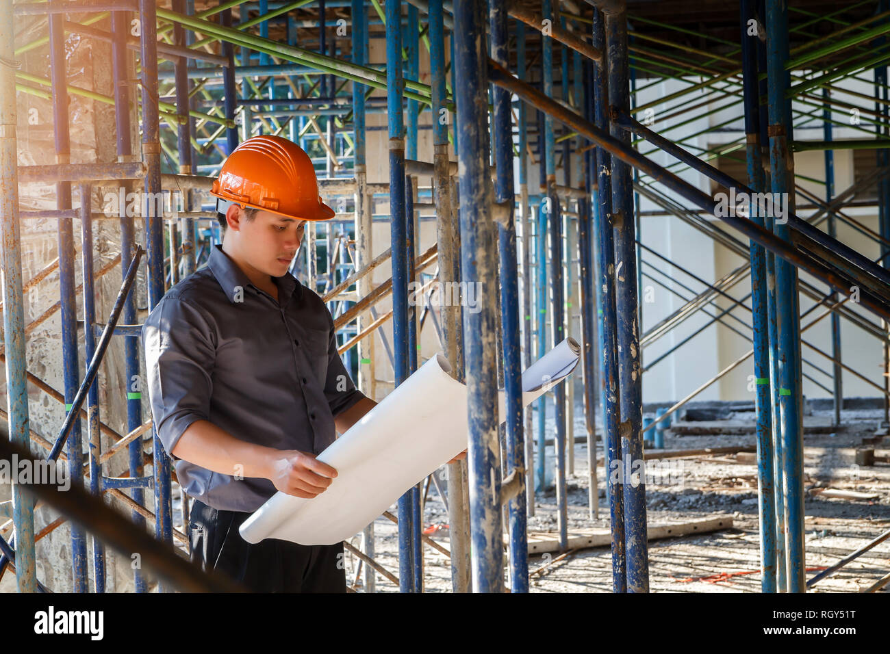 Engineer with blueprint in building construction site Stock Photo - Alamy