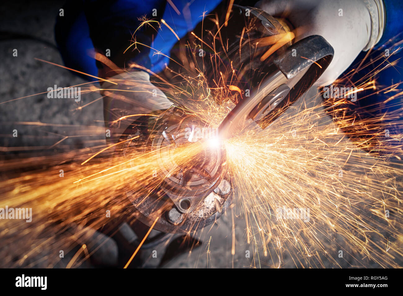 A close-up of a car mechanic using a metal grinder to cut a car part in ...