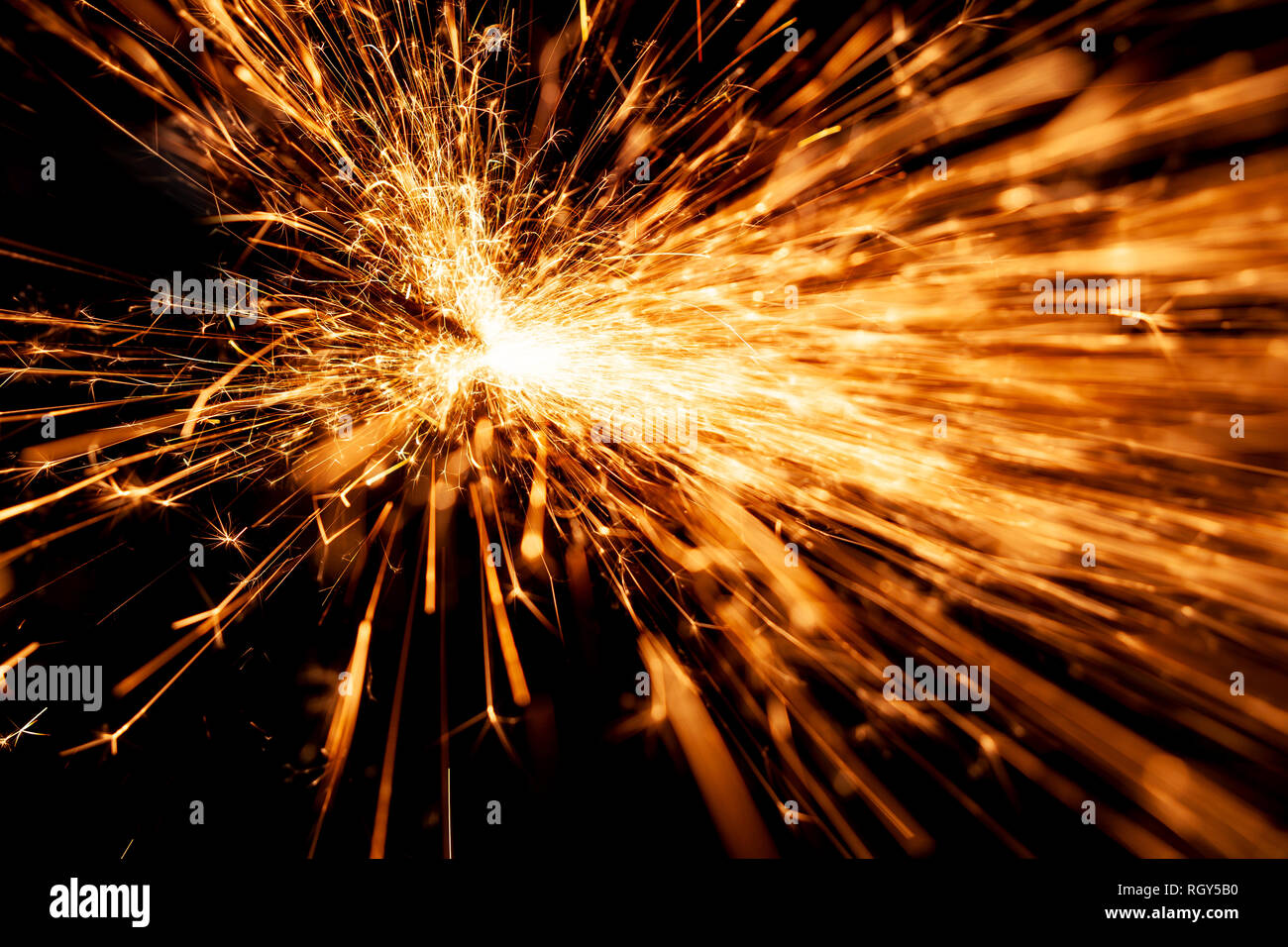 Bright orange and yellow sparks on a black background. A stream of ...