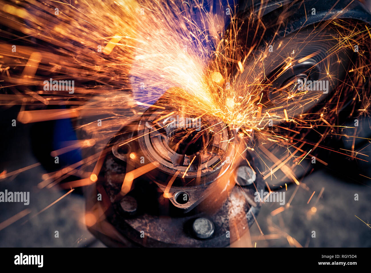 A close-up of a car mechanic using a metal grinder to cut a car part in ...