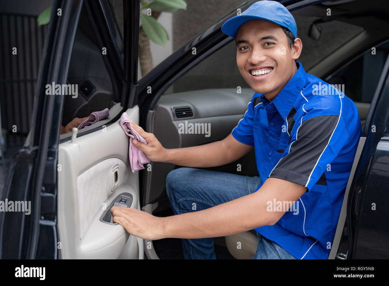 Auto service staff in blue uniform cleaning car Stock Photo - Alamy