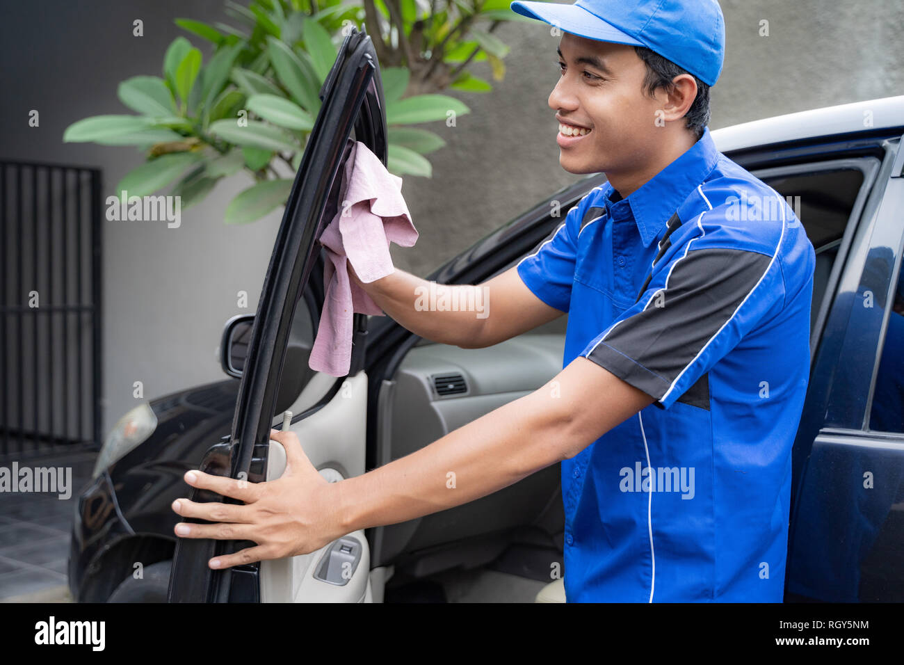 Auto service staff in blue uniform cleaning car Stock Photo - Alamy