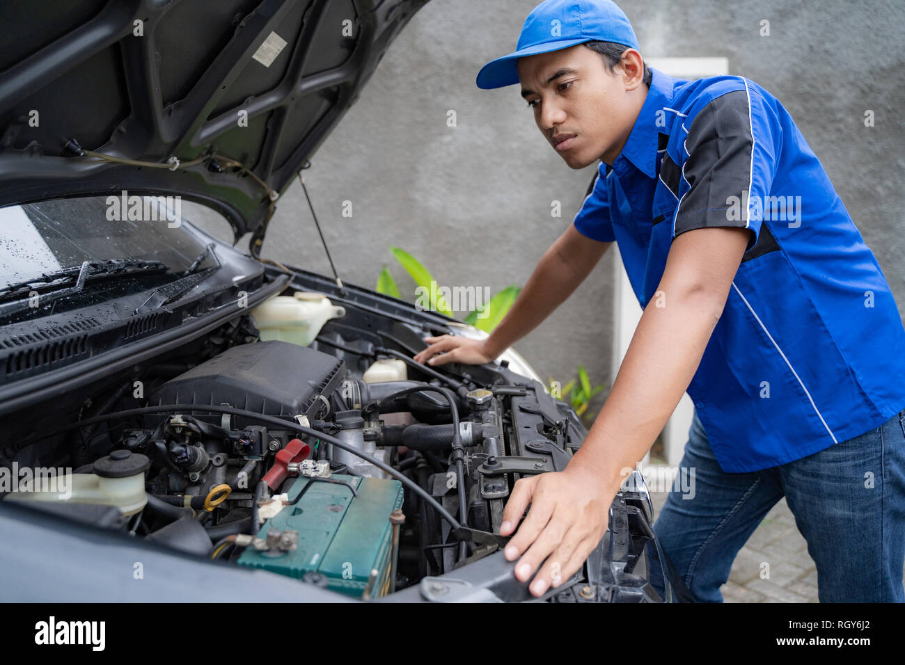blue uniform car engineer worker looking into car's engine Stock Photo ...
