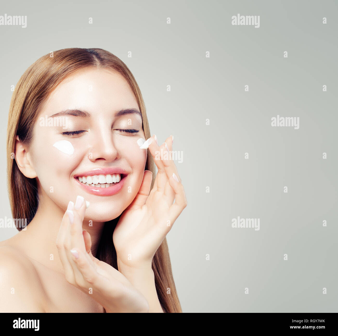 Laughing woman with healthy skin applying moisturizing cream on her ...