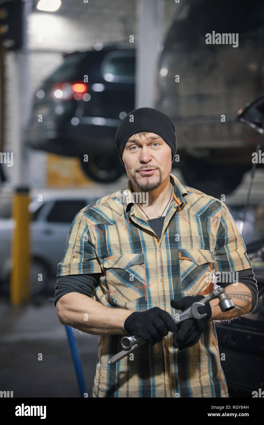 Car service. Brutal mechanic man standing and holding tools Stock Photo - Alamy