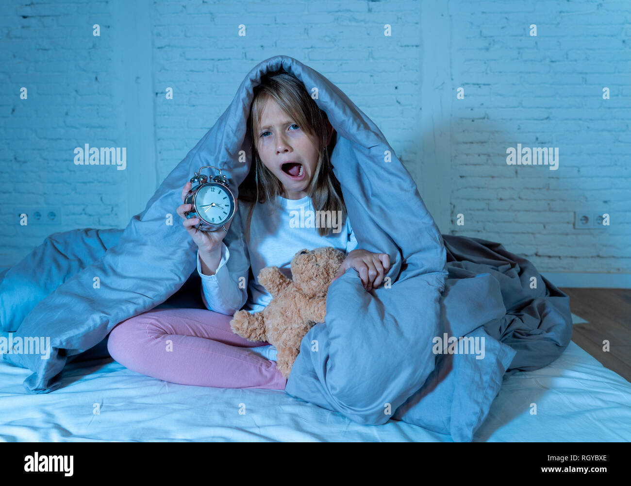 Cute sleepless little girl sitting on bed looking sad and tired having ...