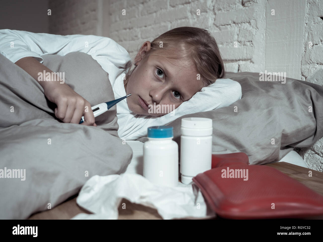Sweet sick cute girl feeling sick lying in bed with medicines ...