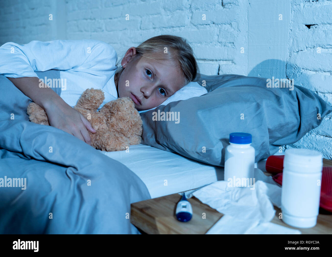 Sweet sick cute girl feeling sick lying in bed with medicines ...