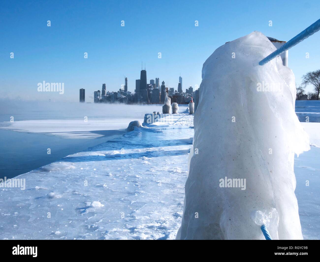 Frozen Lake Michigan with steam rising and a frozen pier covered in ice ...