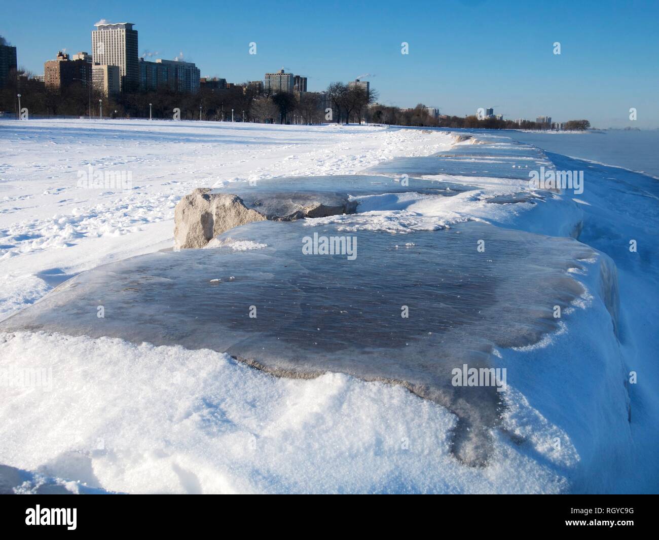 Sheet of ice on walking rocks by Lake Michigan and ground covered in ...