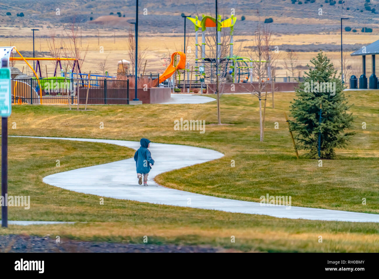 Child on a pathway leading to colorful playground Stock Photo - Alamy