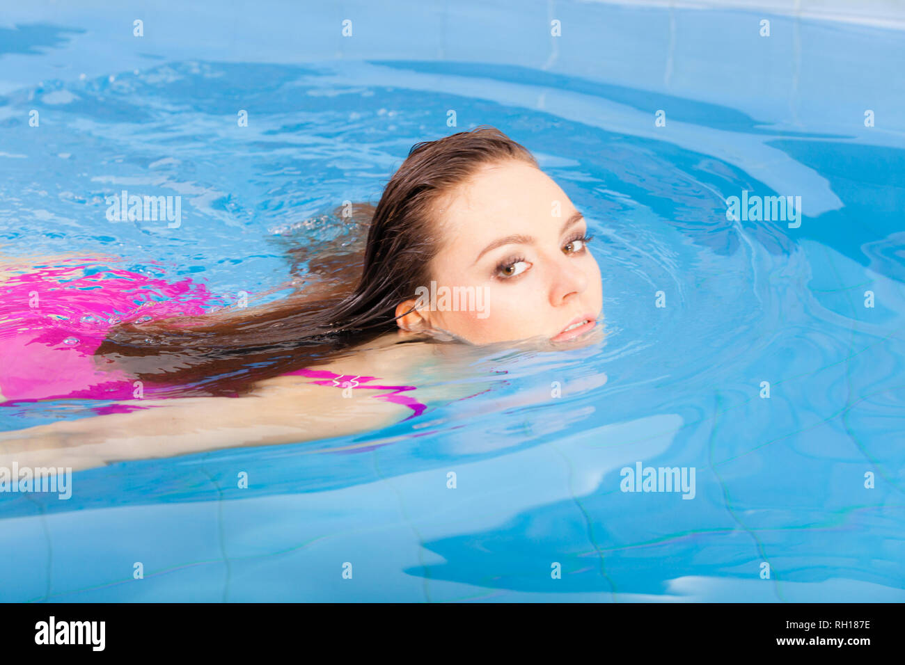 Beautiful young woman in pink swimsuit swimming in blue pool. Young ...