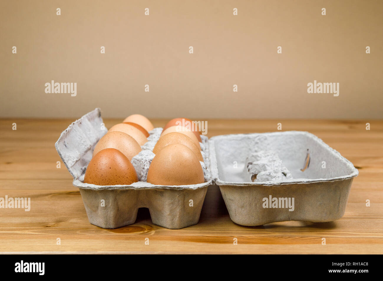 Side view of ten chicken eggs in a carton box on a table with copy ...