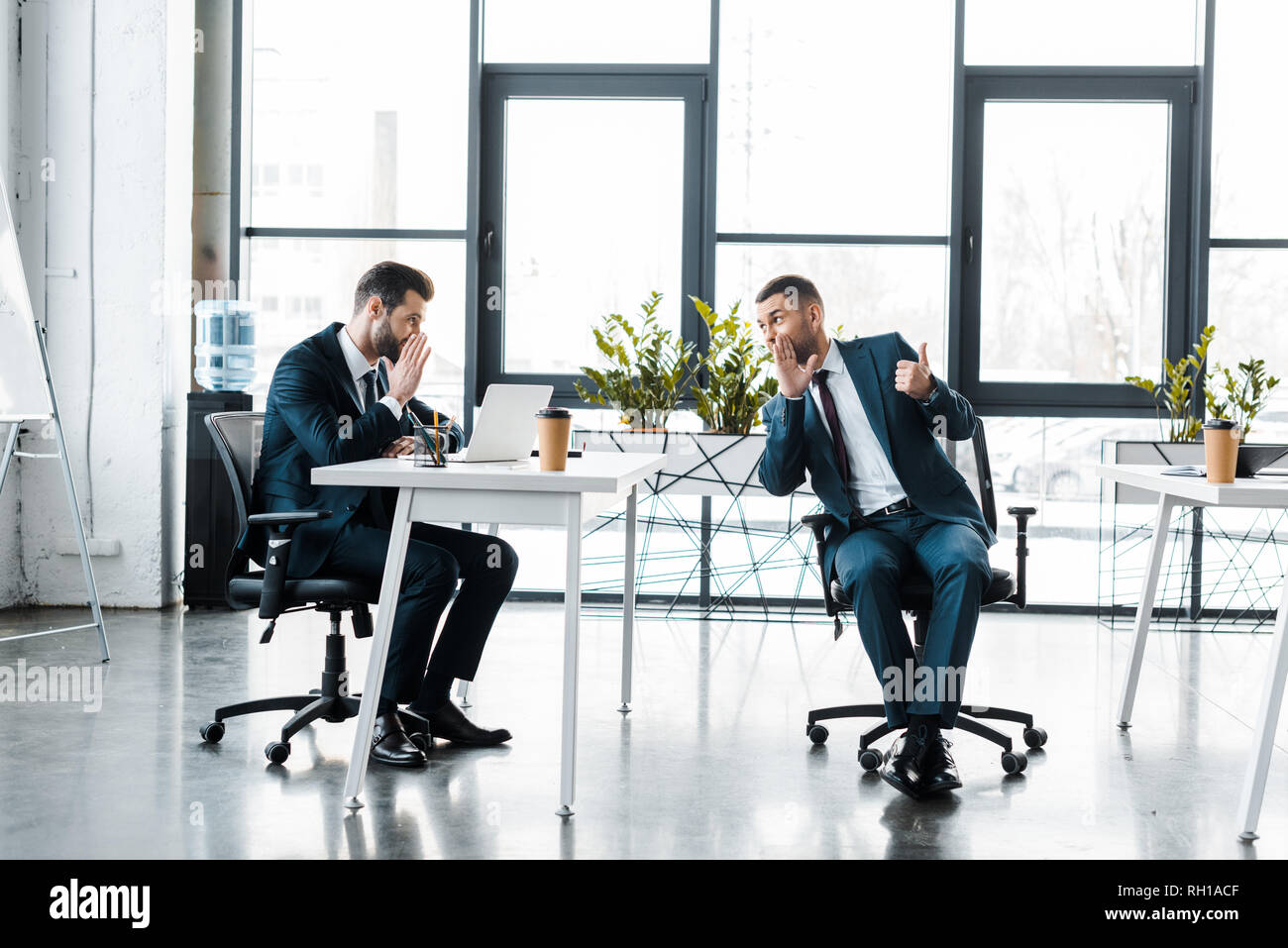 businessmen in formal wear gossiping while sitting in modern office Stock Photo - Alamy