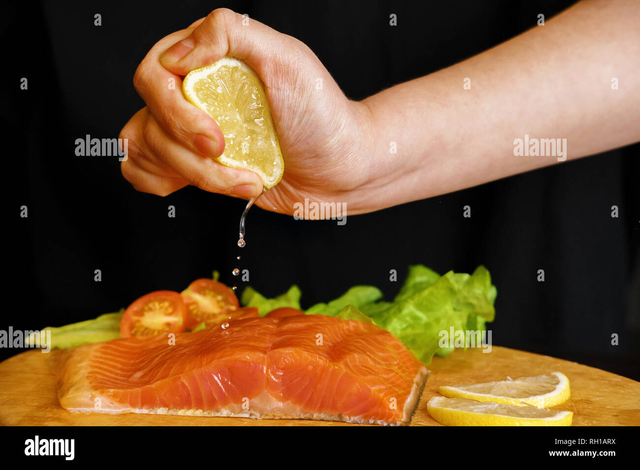 female hand with lemon juice splashes red fish Stock Photo - Alamy