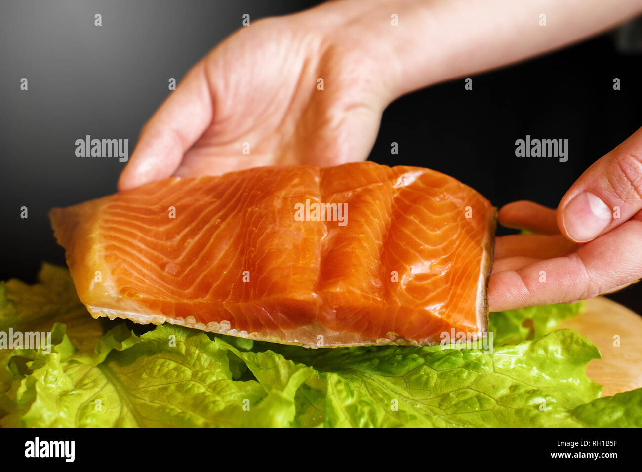female hand with a big piece of red fish Stock Photo - Alamy