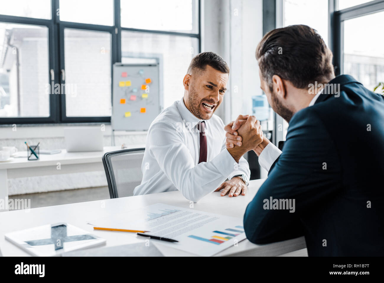 handsome businessman competing arm wrestling with coworker in modern ...