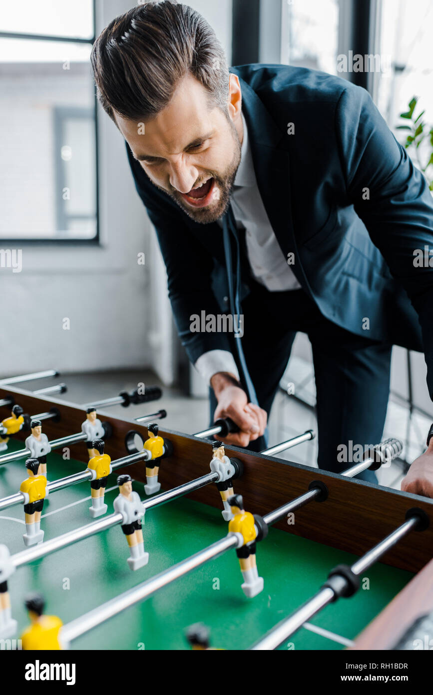 happy bearded businessman in formal wear playing table football Stock ...