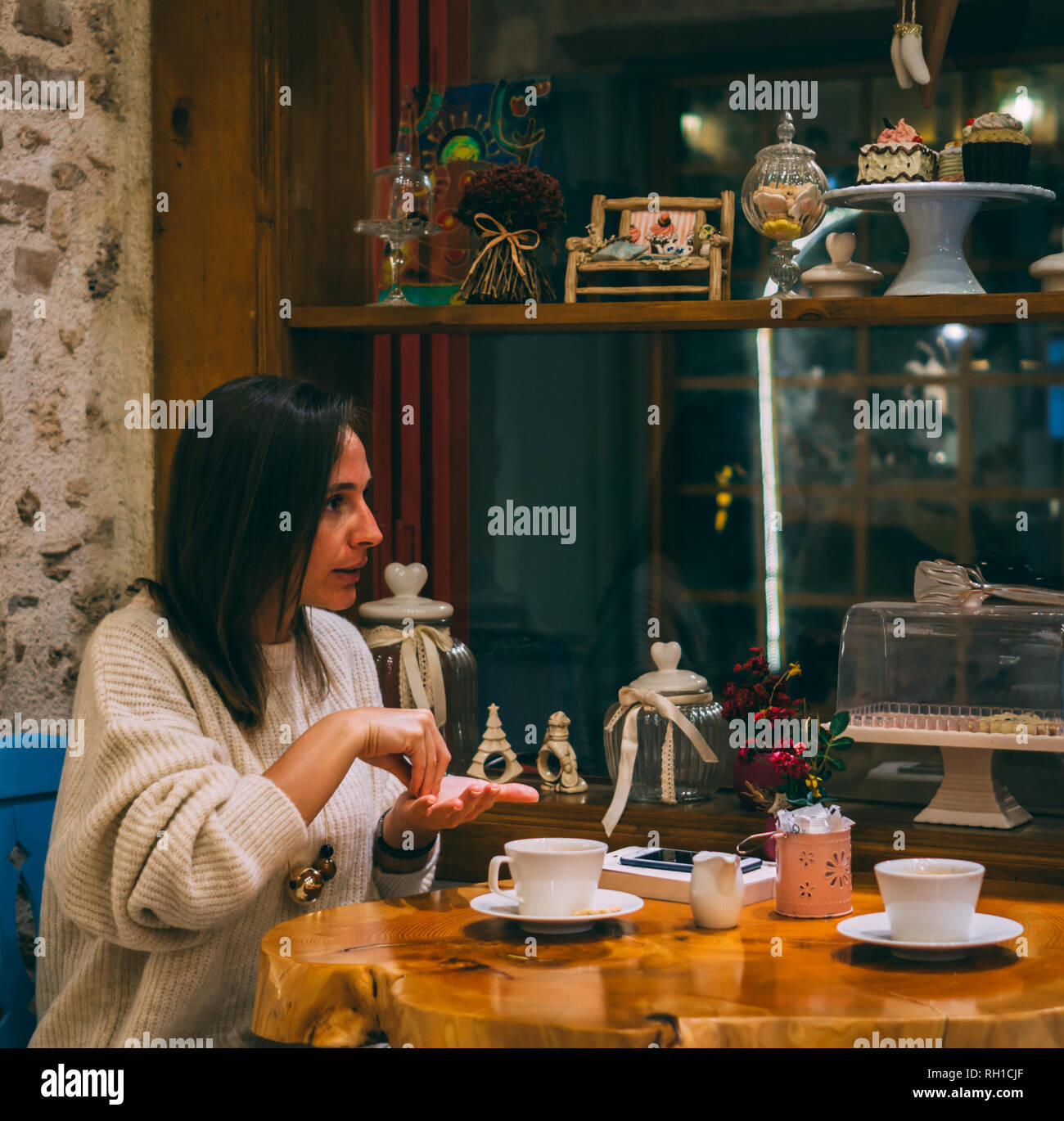 Young woman sitting in cafeteria and talking with sign language. Lady ...