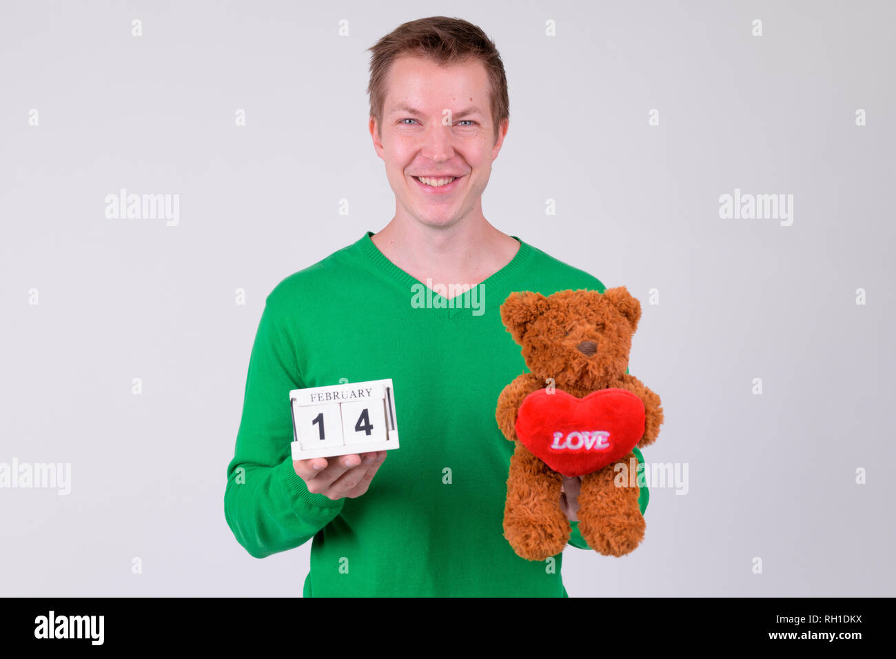Happy young man holding calendar block and teddy bear for Valentine's ...