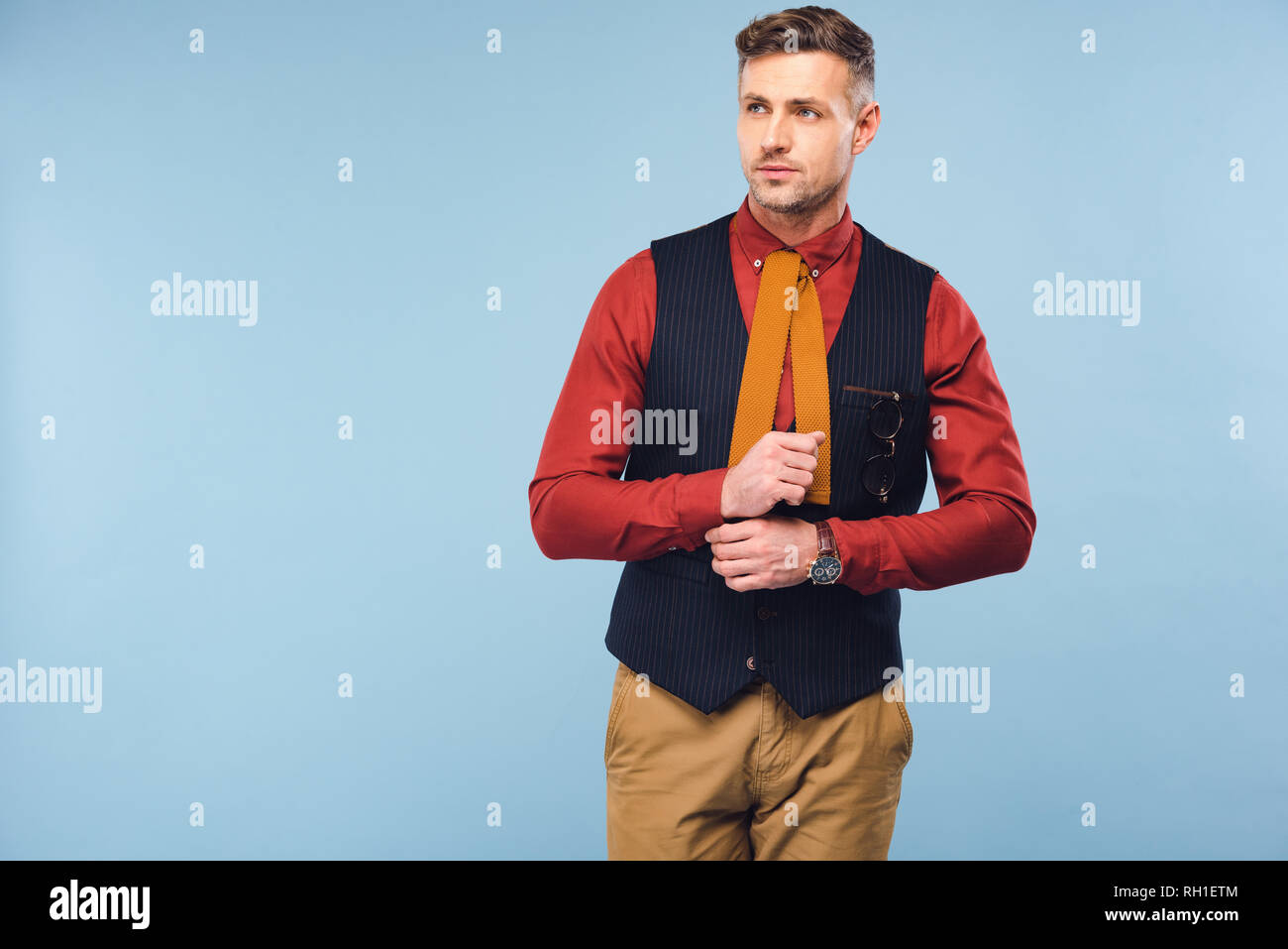 handsome stylish man in formal wear adjusting shirt and looking away ...