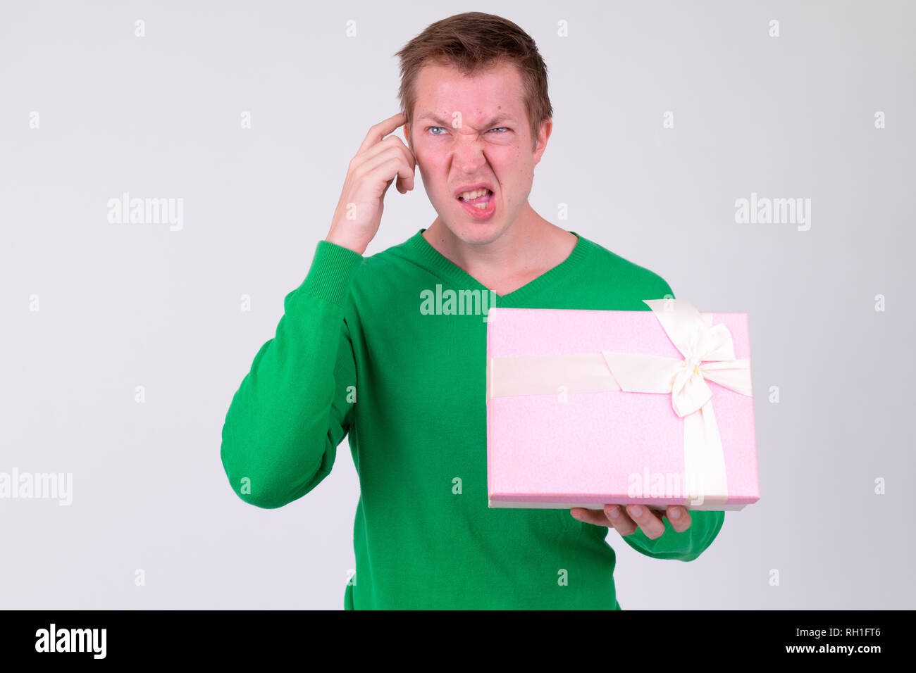Confused young man thinking while holding gift box Stock Photo - Alamy