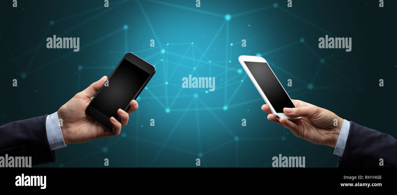 Close up of two hands holding smartphones to each other, wireless ...